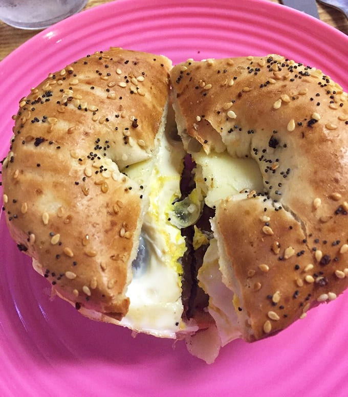 A sausage sandwich on a sesame bagel that's so perfectly constructed, it deserves its own engineering degree and possibly a parade in its honor.