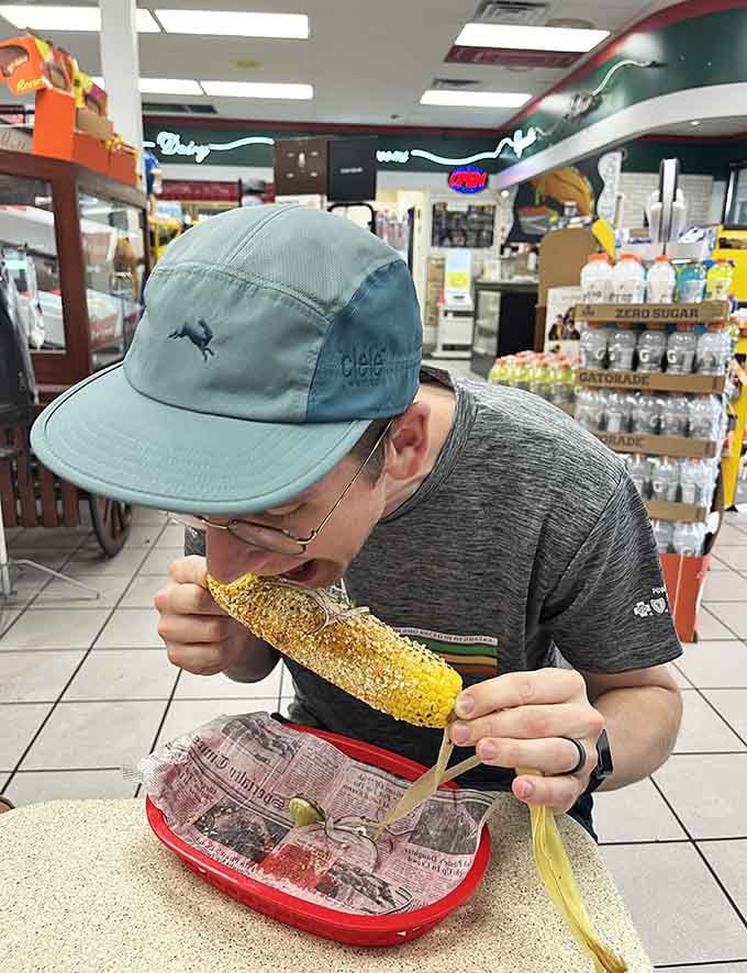 A young diner tackles an elote with enthusiasm, showing that El Sazon's appeal spans generations and that corn on a stick is universally beloved.