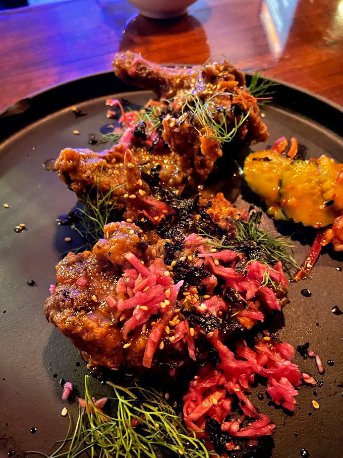 Crispy fried chicken pieces glisten with sauce, perfectly positioned atop a colorful vegetable medley &ndash; indulgence meets artistry on a plate.