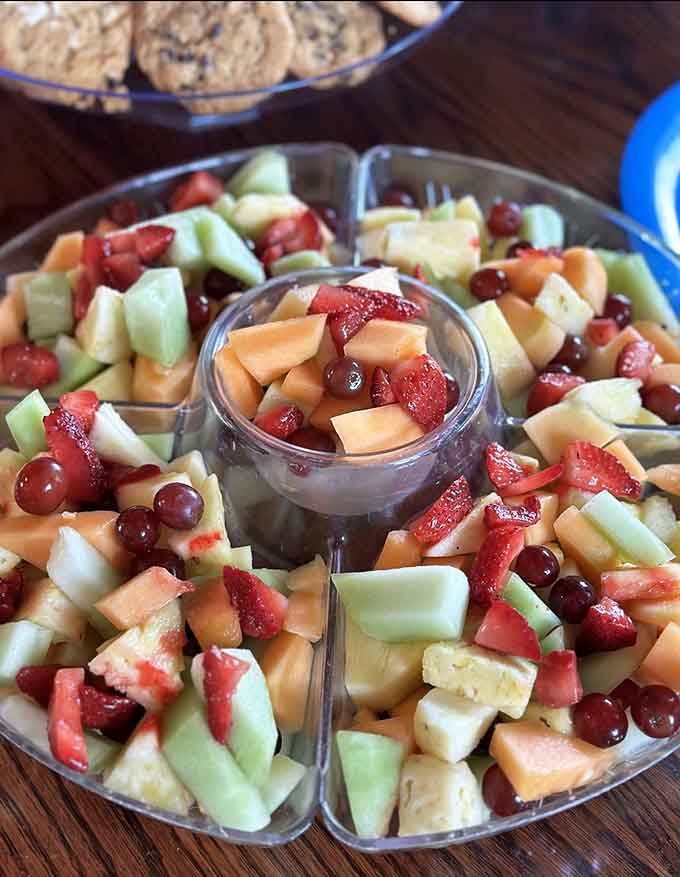 Fresh fruit salad arrives in a generous portion that's almost too pretty to eat, with strawberries, melon, and grapes arranged like edible art.