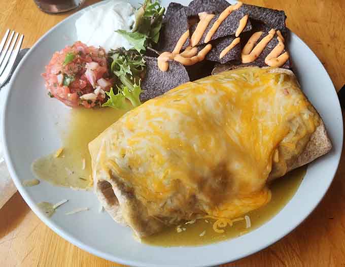 This breakfast burrito arrives smothered in cheese and green chile sauce, ready to fuel your North Shore adventures properly.