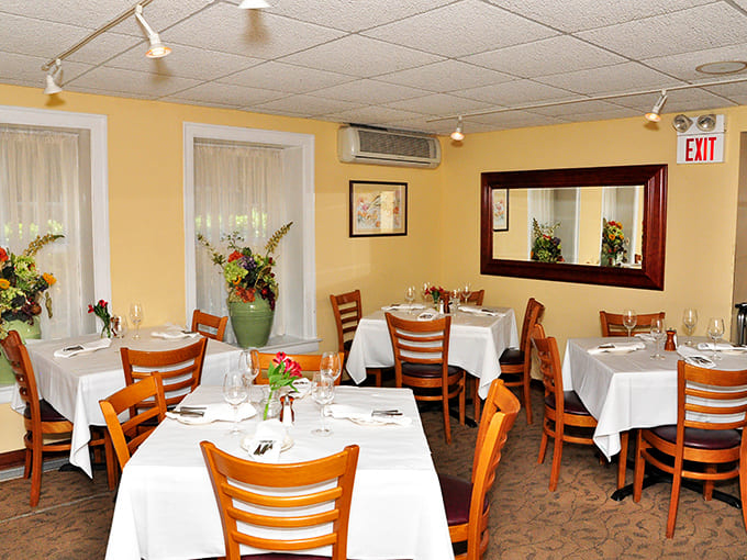 The main dining room exudes warmth with its yellow walls and white tablecloths, creating an inviting space where memorable meals unfold at a leisurely pace.