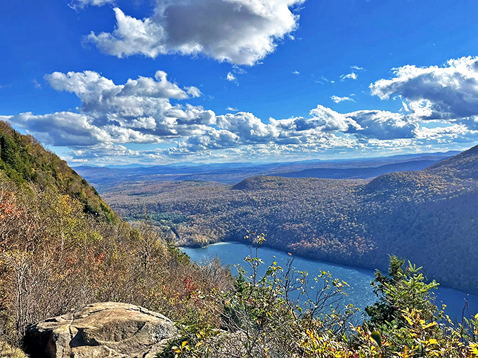Lake Willoughby shimmers below like nature's mirror, reflecting clouds that seem close enough to touch from this lofty perch.