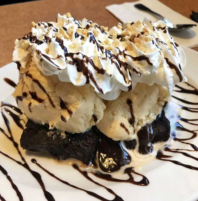 Chocolate decadence at its finest: a warm brownie foundation supports scoops of vanilla ice cream, whipped cream, and chocolate drizzle architecture.