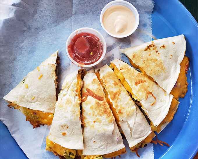 Quesadilla triangles grilled to golden perfection with sides of salsa and sour cream for dipping, because balance matters.