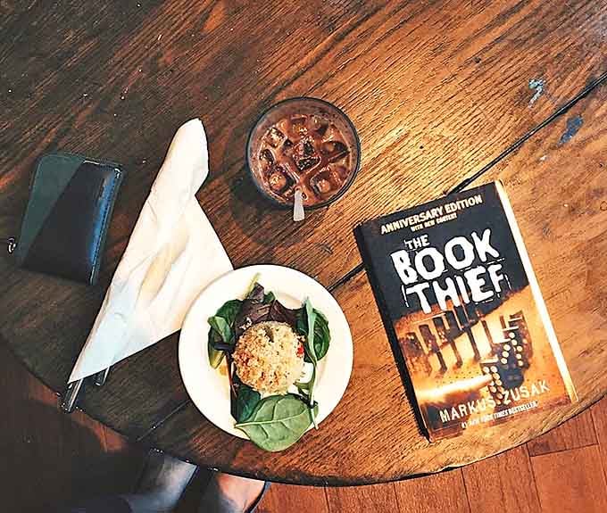 The perfect trifecta: Markus Zusak's "The Book Thief," a refreshing iced coffee, and a healthy grain salad for sustained reading energy.