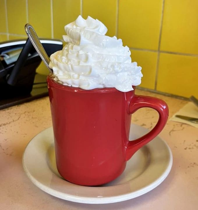 This hot chocolate's whipped cream tower defies physics and probably violates several laws of thermodynamics, but who's complaining?