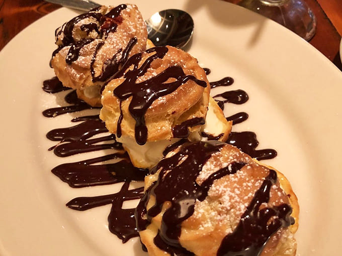 Profiteroles drizzled with chocolate sauce like edible works of art, because life's too short to skip dessert at historic restaurants.