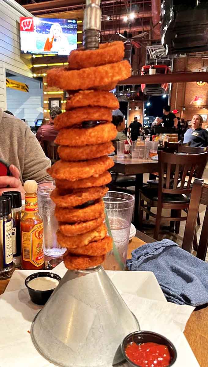 The onion ring tower defies both gravity and restraint, stacked higher than your willpower with golden rings demanding to be devoured.