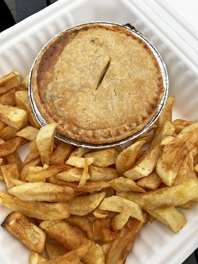 A savory pie surrounded by a fortress of chips &ndash; the ultimate British comfort food combination that satisfies both the eye and stomach.