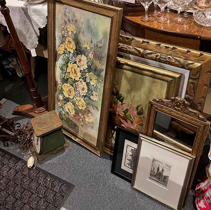 Vintage frames and artwork lean together in artistic chaos, proving that one person's attic cleanout is another's decorating goldmine.