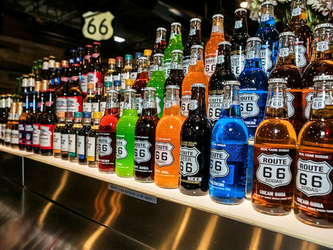 A rainbow of Route 66 sodas stands at attention, proving that sometimes the best road trip souvenirs come in liquid form.