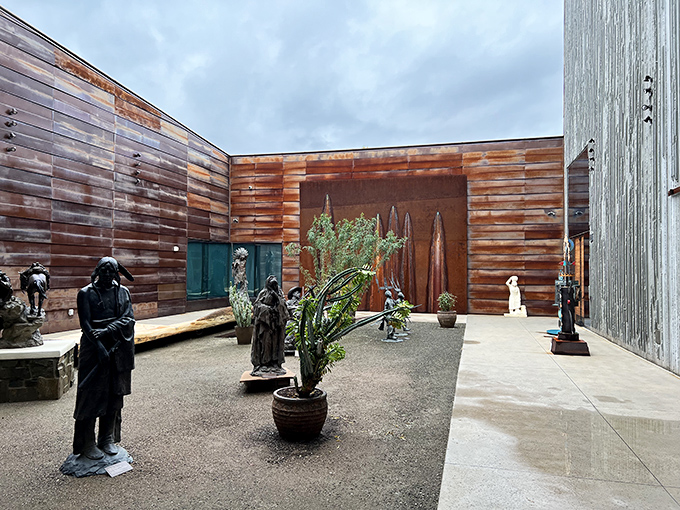 Bronze sculptures stand sentinel in the outdoor courtyard, frozen in time against weathered copper walls.