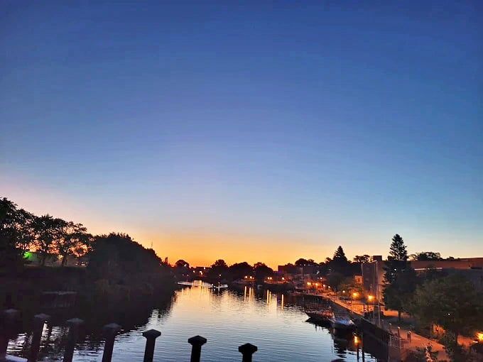 Sunset transforms the Manistee River into liquid gold, that magical hour when day surrenders to night in a spectacular Michigan light show.