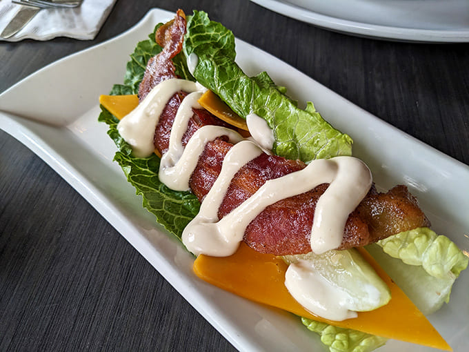 Bacon gets the royal treatment &ndash; crispy, savory strips nestled on fresh greens with a drizzle of house-made sauce that makes everything better.