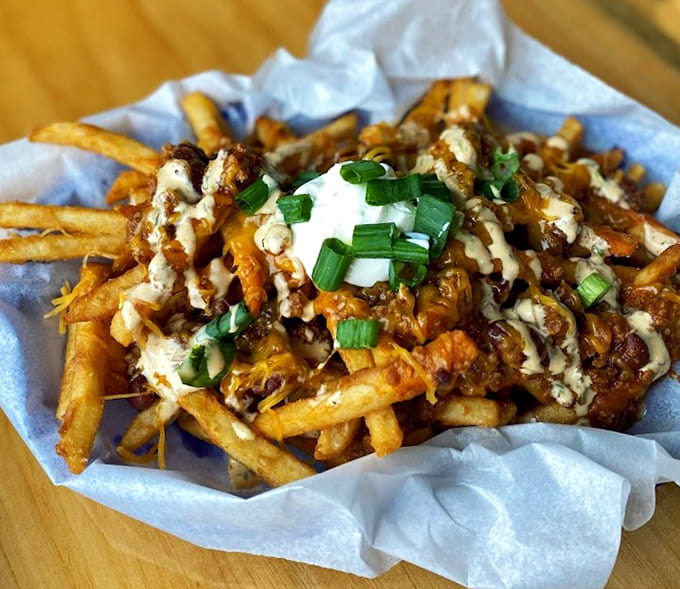 Loaded fries topped with cheese, bacon, and sour cream represent the kind of delicious excess that makes diets seem like distant memories.