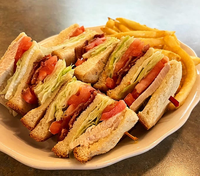 This turkey club sandwich stacks up like an edible skyscraper, requiring both hands and possibly an engineering degree to eat properly.