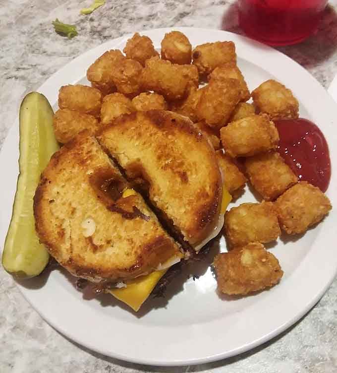 The grilled cheese sandwich with tater tots offers a nostalgic combination that hits all the right comfort food notes.