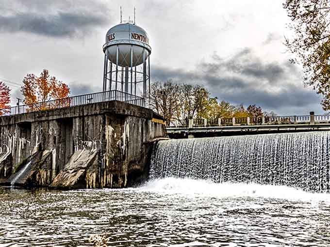 West Branch Falls creates a mesmerizing curtain of water, with the town's water tower standing sentinel in the dramatic background.