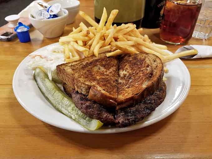 A towering Reuben sandwich with a mountain of fries represents the kind of lunch that requires both hands and possibly a nap afterward.