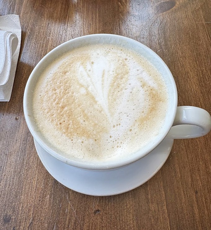 Coffee art so pretty you almost don't want to drink it. Almost. The wooden table underneath has heard thousands of "mmms" over the years.