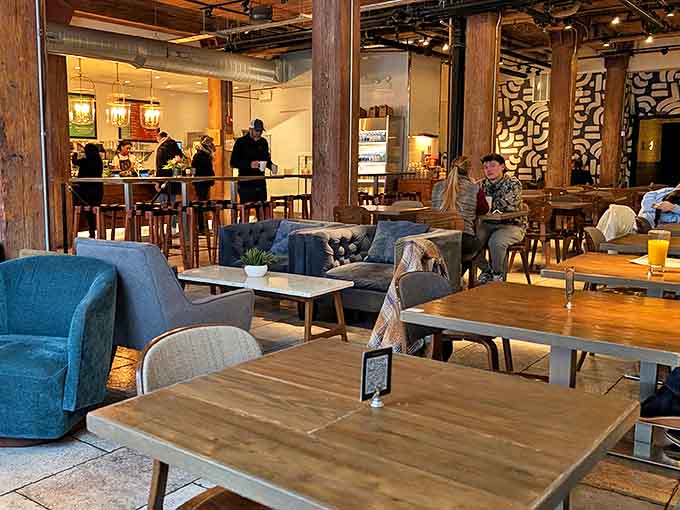 Conversations bloom between wooden tables and blue couches, each patron finding their perfect spot in this caffeinated sanctuary.