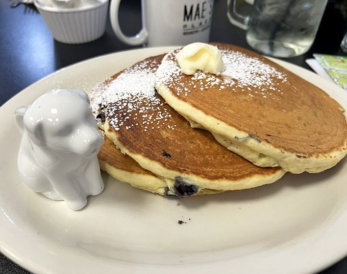 Pancakes that deserve their own zip code, complete with a little butter-melting divot and a cute ceramic puppy syrup guardian standing watch.