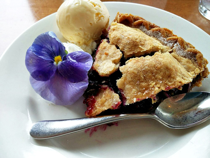 Mixed berry pie crowned with vanilla ice cream offers a sweet finale, the flaky crust giving way to warm, jammy fruit that captures summer's essence.