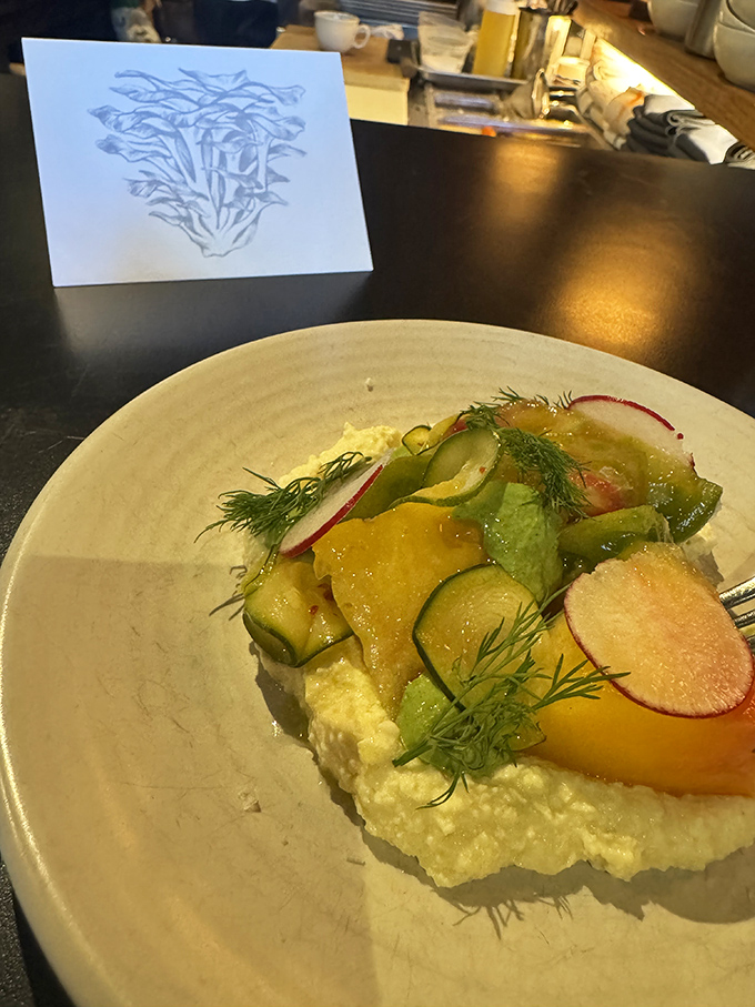 Seasonal vegetables transformed into an artistic composition &ndash; bright radishes, cucumber, and herbs dancing atop a creamy base that balances texture and flavor.