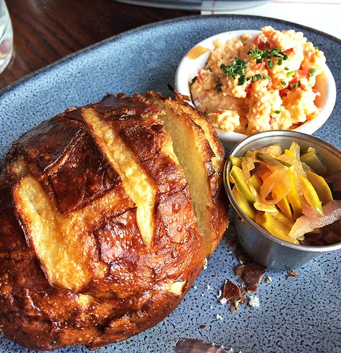 Start your meal right with our crusty, house-baked sourdough bread served alongside flavorful spreads and tangy pickled vegetables.