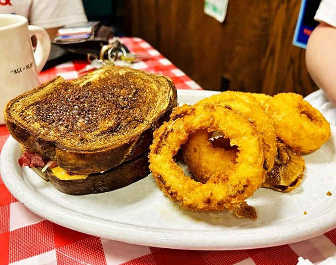 The Reuben sandwich and onion rings combo &ndash; a study in textural contrasts with golden-fried rings beside the melty, savory sandwich.