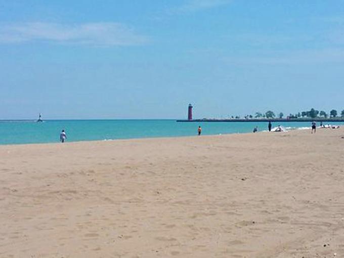 A red lighthouse stands sentinel over golden sands. It's like a postcard come to life!
