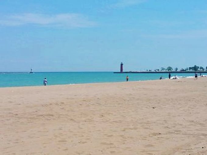A red lighthouse stands sentinel over golden sands. It's like a postcard come to life!