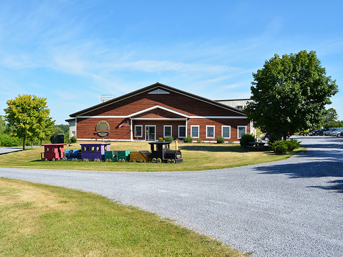 A charming brown wooden building welcomes visitors with colorful toy trains dotting the lawnlike a storybook come to life.