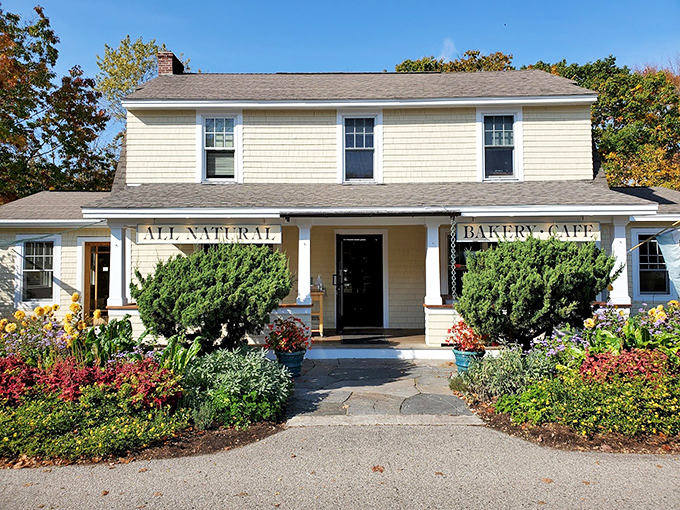 A charming yellow colonial house transformed into bakery heaven, complete with blooming gardens that say "Welcome to carb paradise!"