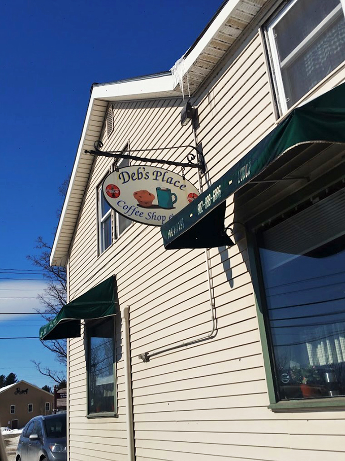 A charming white clapboard building with vintage signage that promises coffee and comfort - Vermont's version of a warm hug.
