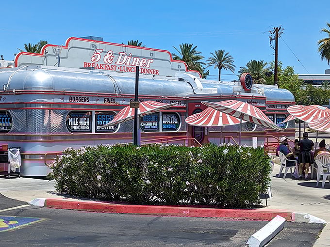 Chrome gleams and neon dreams: The 5 & Diner's exterior shimmers like a time capsule from 1955, complete with retro-striped awnings and desert palm trees. Photo credit: Guido Haesen