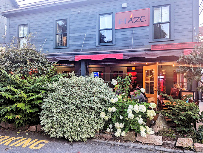 A charming blue building with blooming hydrangeas welcomes you to Blaze, where coastal Maine meets culinary adventure in Bar Harbor.