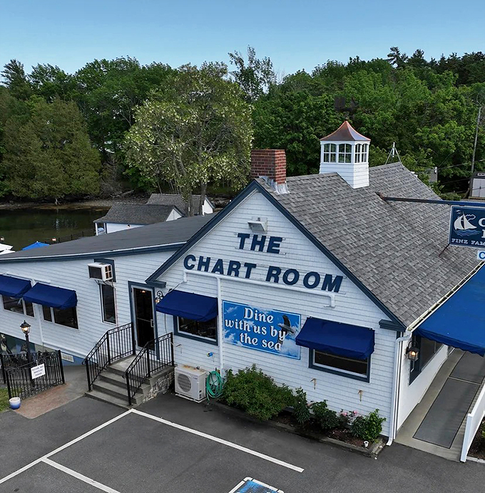 The Chart Room stands proudly against Maine's coastline, its white clapboard exterior and blue awnings beckoning like a lighthouse for hungry souls. Photo credit: Chart Room Harbor