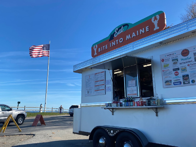 A classic white food truck against a brilliant blue Maine sky, with Old Glory waving proudly &ndash; this is where lobster roll dreams come true. Photo credit: Aaron Bennett