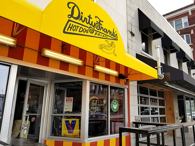 Yellow beacon of hope! Dirty Frank's exterior promises a hot dog adventure with its vibrant awning and inviting patio. Comfort food paradise awaits.