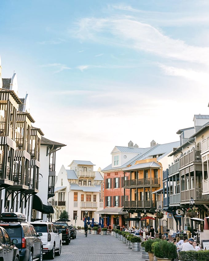 Pastel-colored buildings frame a perfect street view where families and friends chill, while a lone bike moves to its next adventure.