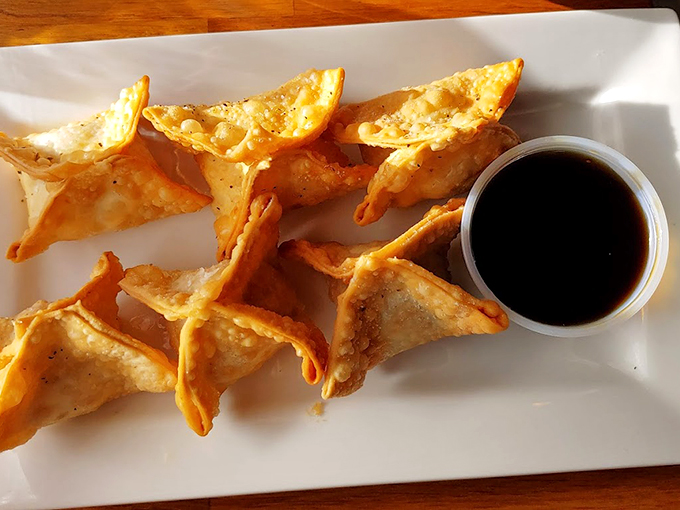 These crispy crab rangoon are like little treasure chests of flavor, complete with their own dark sauce pearl. Photo credit: Joshua Poltrack
