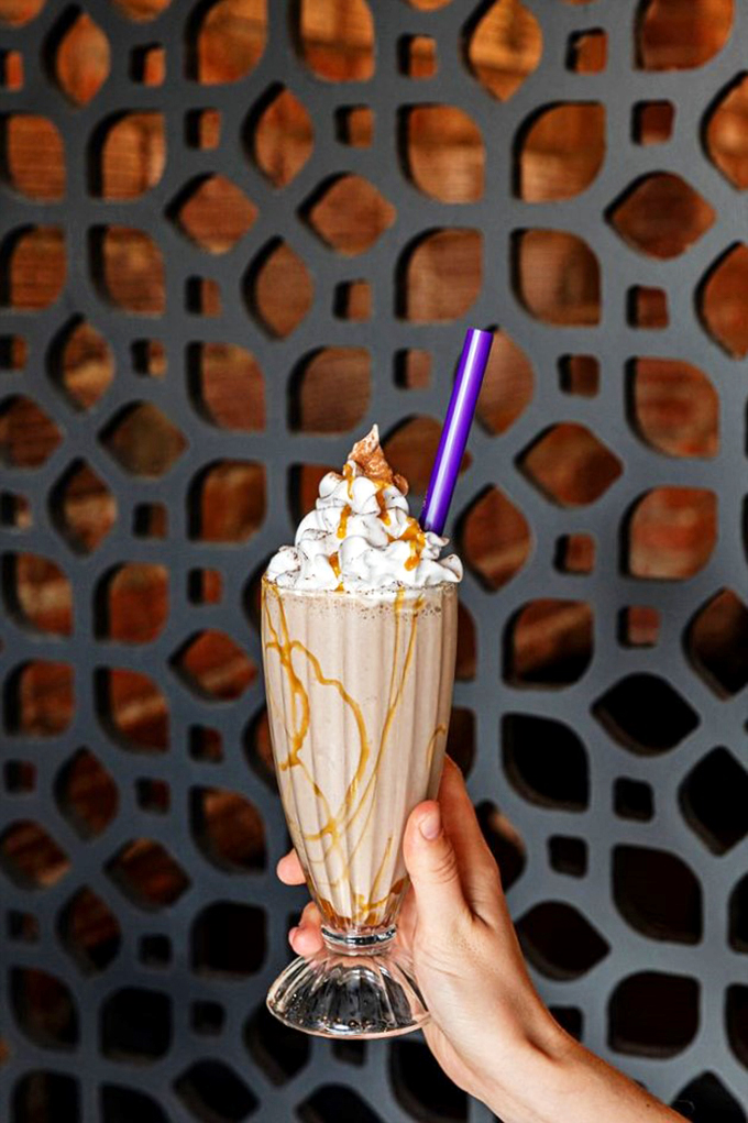 A towering milkshake that looks like it graduated from dessert university with honors in deliciousness.