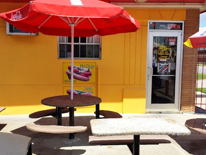 Red umbrellas shade simple picnic tables, creating an urban oasis perfect for summer afternoon noshing.