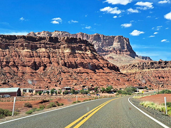 The winding road ahead promises adventure, with vermilion cliffs rising like ancient guardians of the desert. 