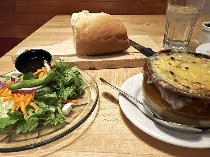 French onion soup wearing a golden cheese crown, accompanied by a garden-fresh salad that keeps things balanced.