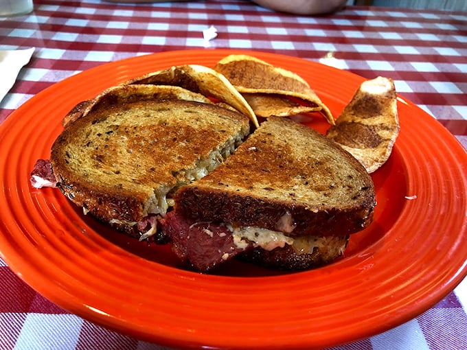 A grilled sandwich that's achieved the perfect golden-brown crunch, served on a fiesta-bright orange plate.