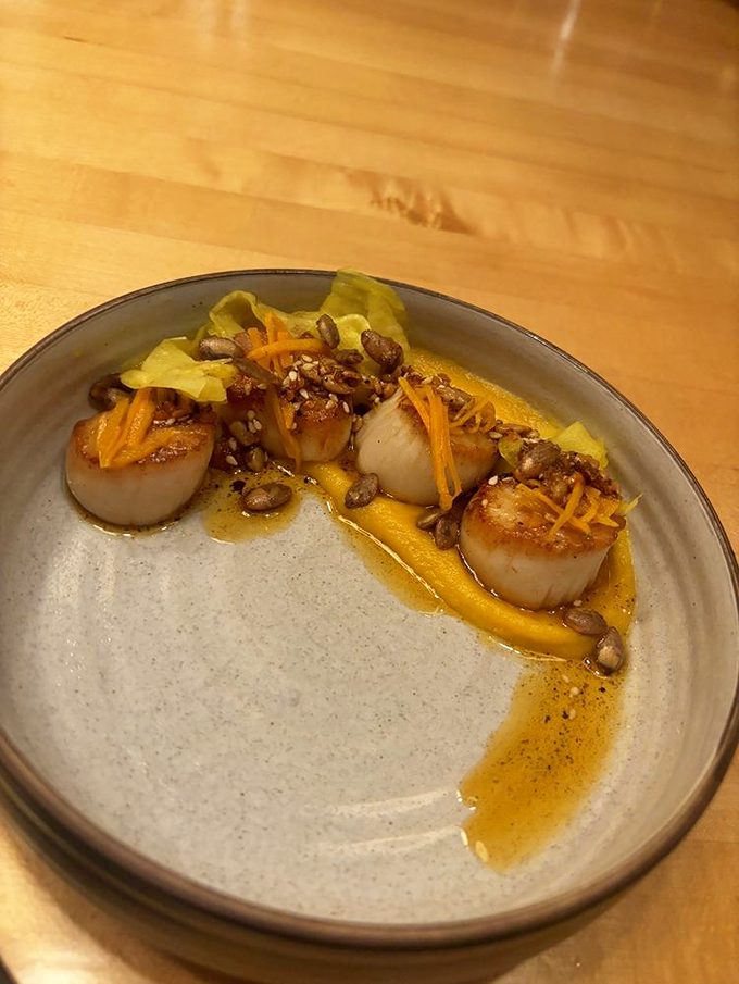 Perfectly seared scallops line up like pearls on a plate, each one a golden testament to precise timing. Photo credit: Eri L.