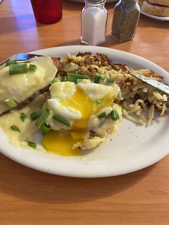 A cascade of hollandaise sauce drapes these eggs Benedict like a silk scarf, with crispy potatoes playing backup.
